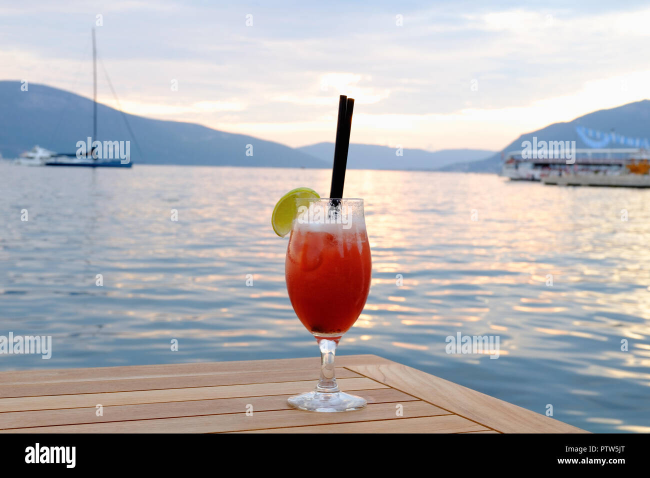 Cocktail glass with lemon on wood table with seascape and skyline in ...