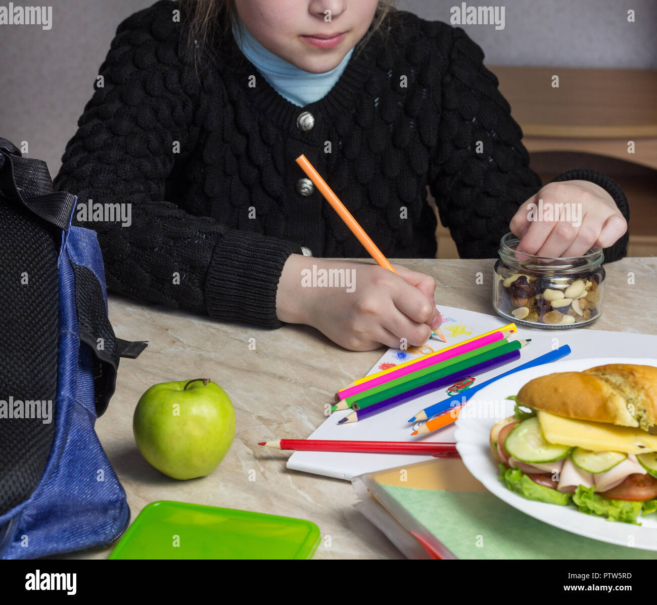 Girl doing homework and eating dried fruits Stock Photo - Alamy