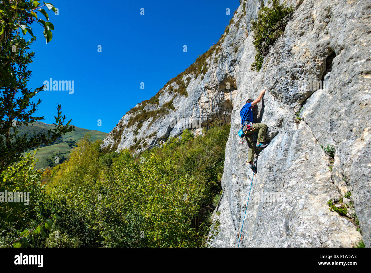 Young male rock climber in blue on steep cliff, Ariege, French Pyrenees ...