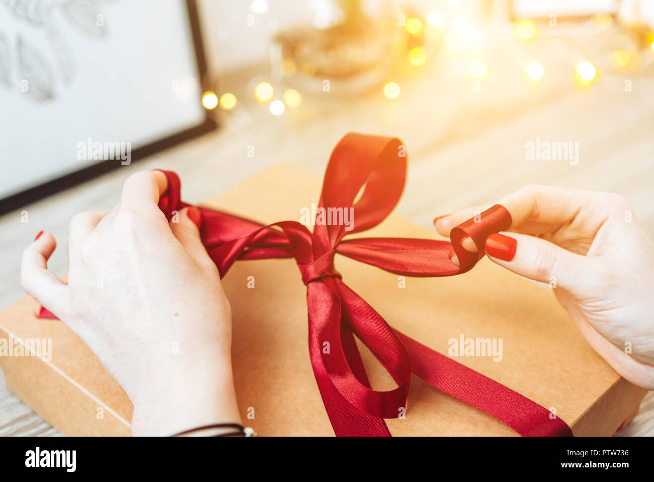Woman wrapping present in paper with red ribbon Stock Photo - Alamy