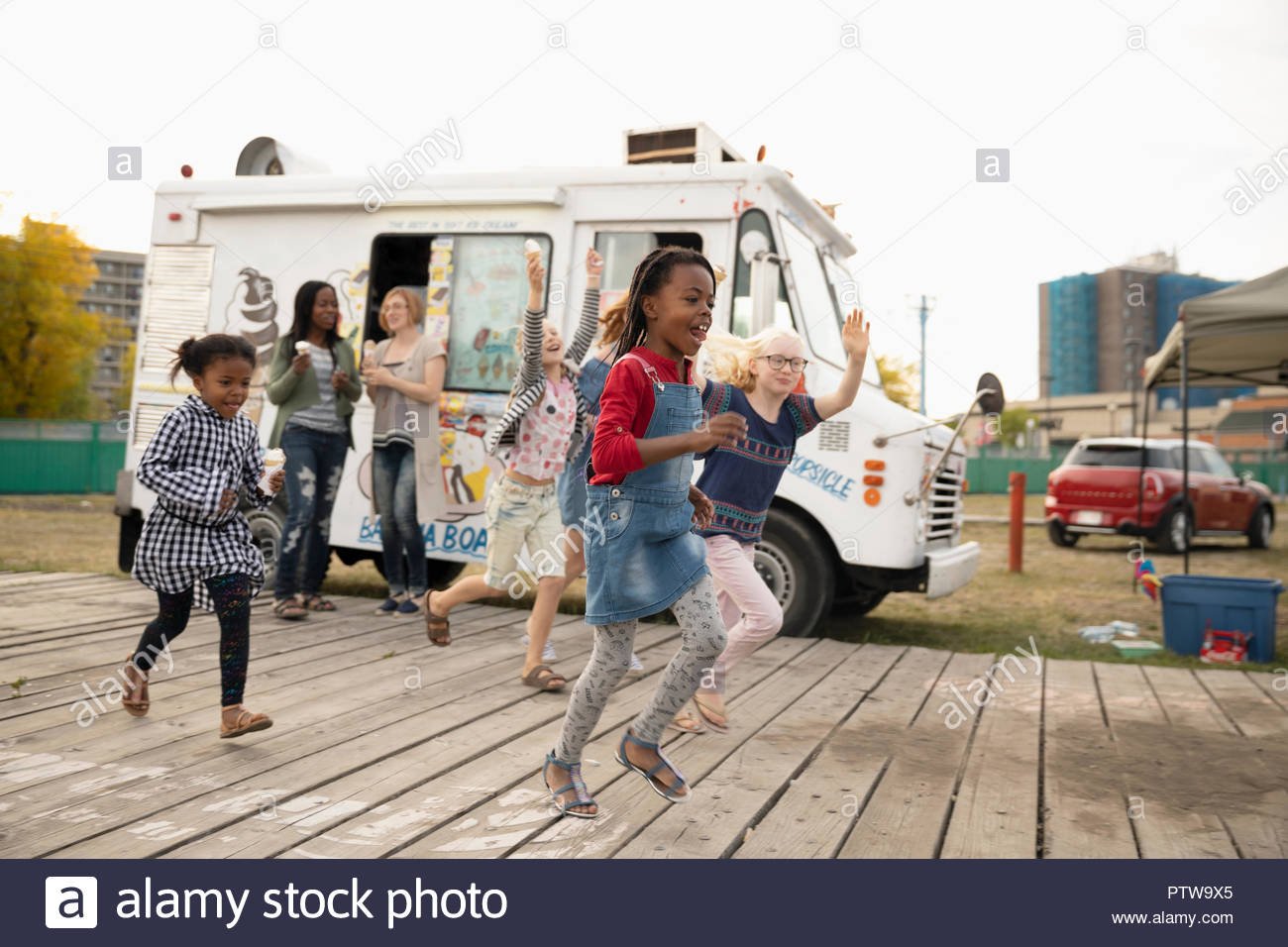 Playful, excited girls running outside ice cream truck Stock Photo - Alamy