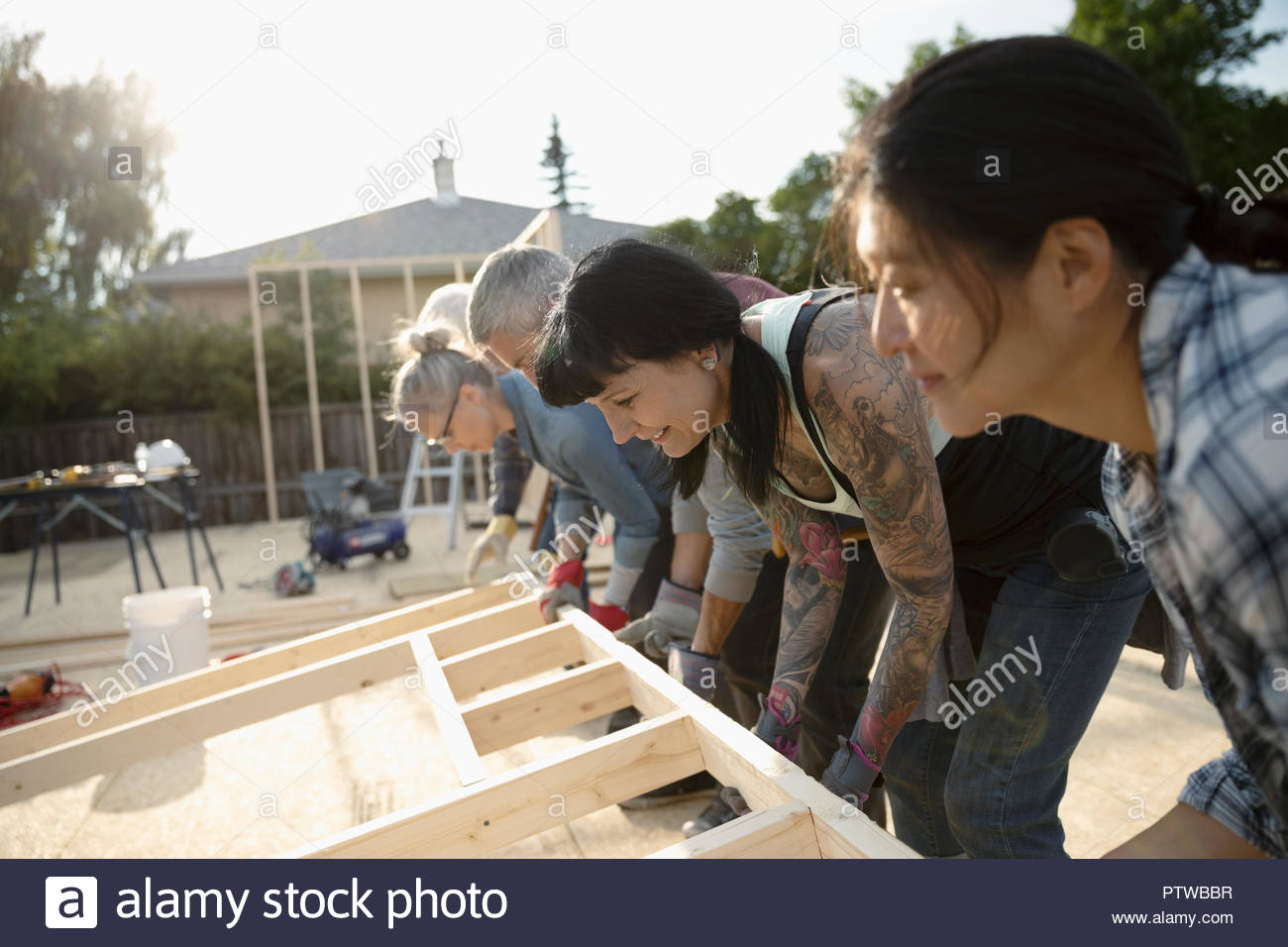 Volunteers lifting frame, helping build house Stock Photo - Alamy