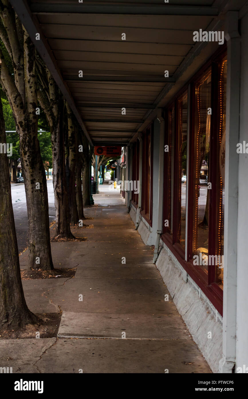 Empty retail storefront covered sidewalk with trees Stock Photo - Alamy