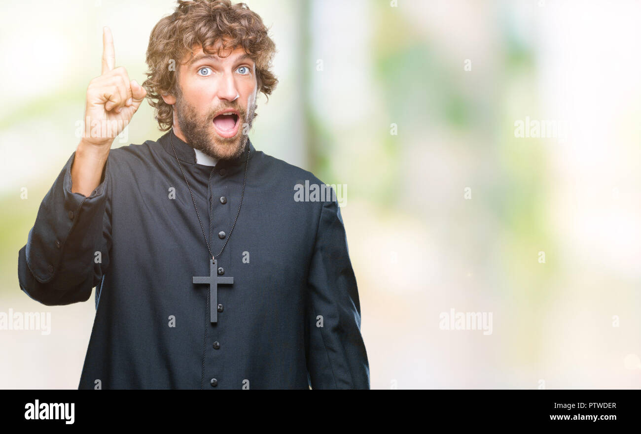 Handsome hispanic catholic priest man over isolated background pointing ...