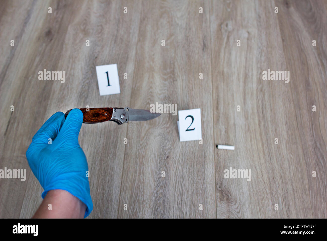 Folding knife and cigarette butt on a wooden background, investigation ...