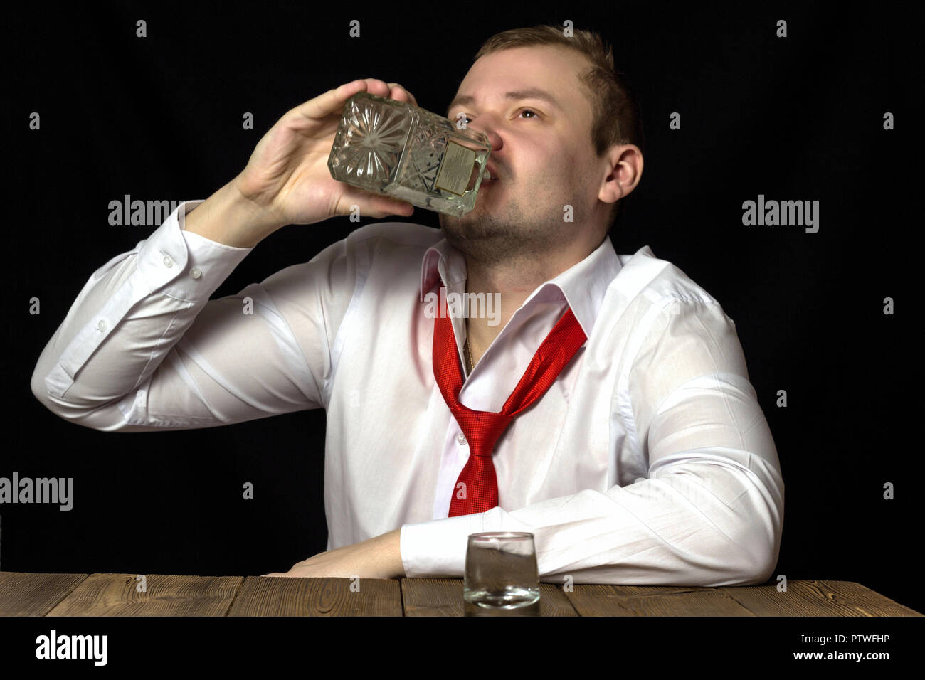 Male businessman in white shirt and tie drinks alcohol from bottle ...