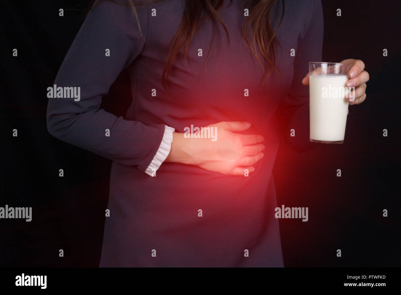 The girl on a black background holds on to her stomach and holds in her ...