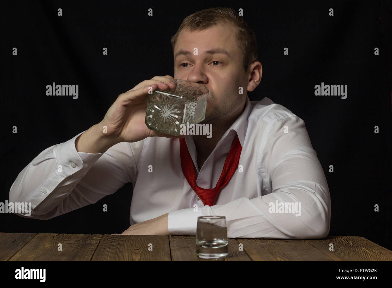 A man in a white shirt and tie drinks alcohol from a bottle, male ...