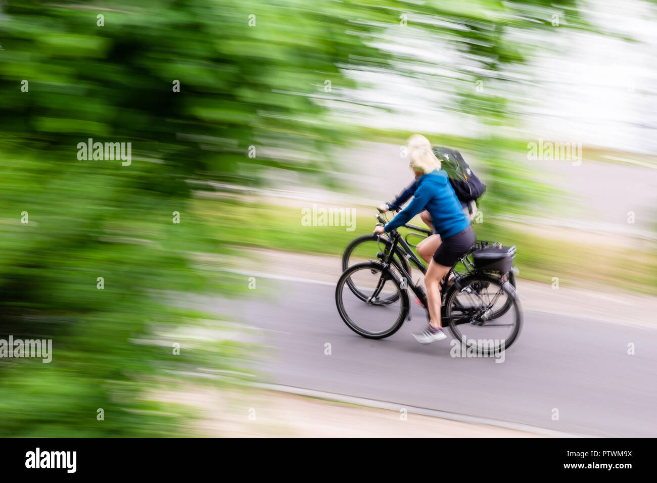 two bicycle riders on a cycle path with camera made motion blur effect ...