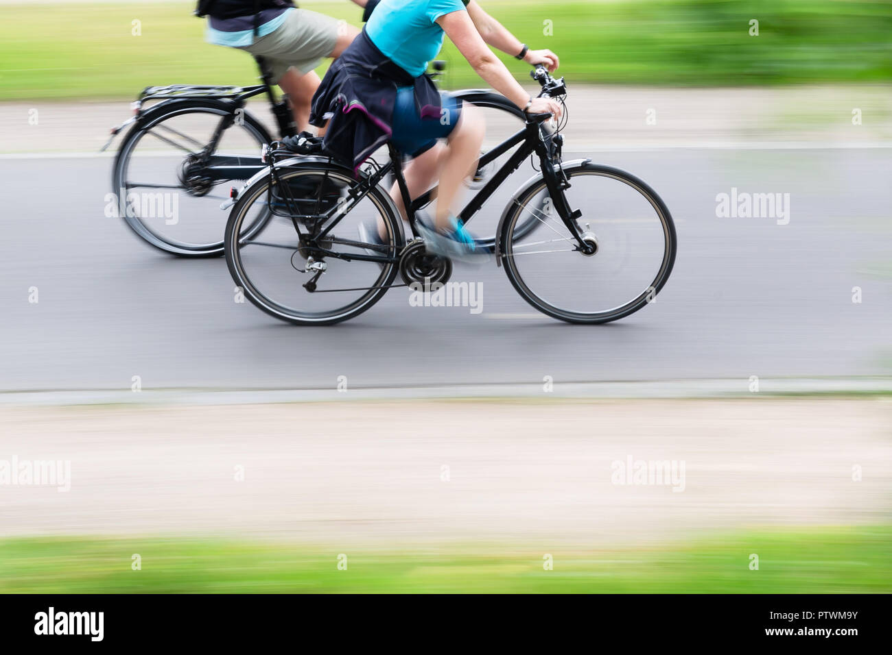 two bicycle riders on a cycle path with camera made motion blur effect ...