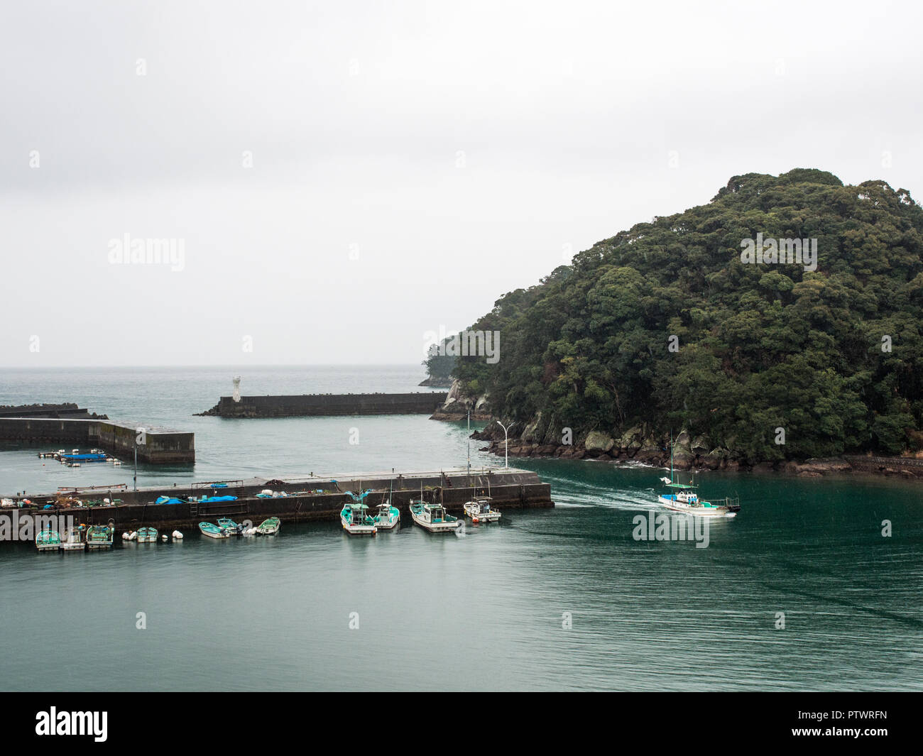Fishing boat entering harbour, protected by breakwaters, Shishikui ...