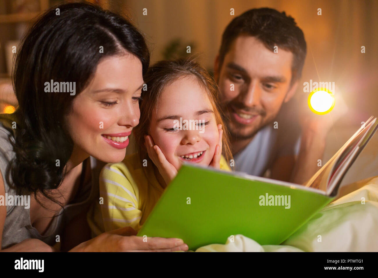 happy family reading book in bed at night at home Stock Photo - Alamy