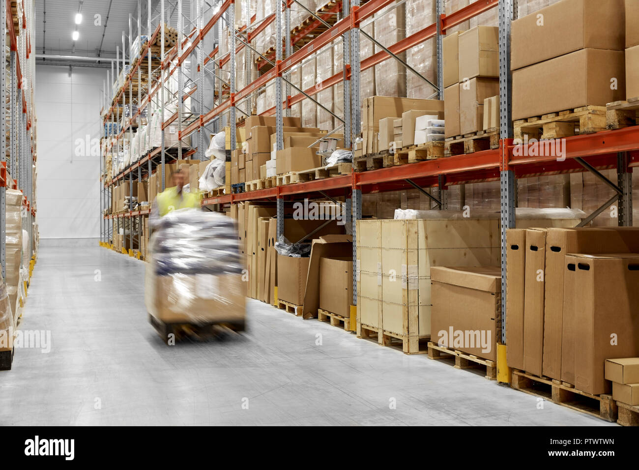 worker carrying loader with goods at warehouse Stock Photo - Alamy