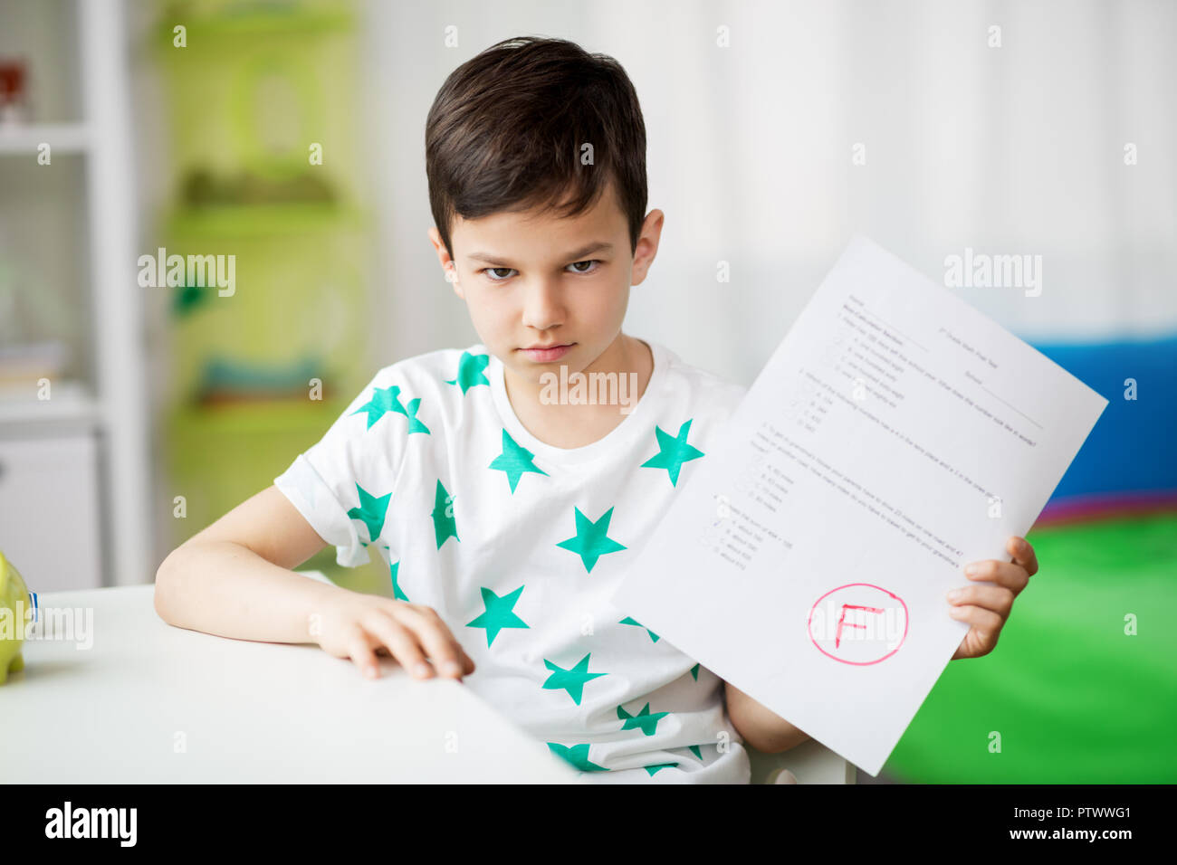 sad boy holding school test with f grade Stock Photo - Alamy