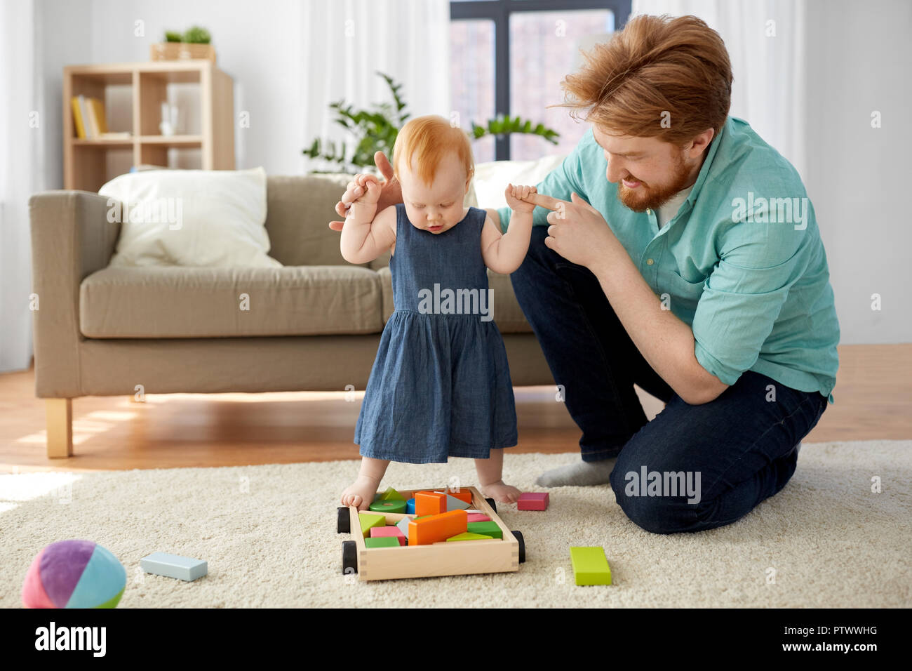 baby girl standing with father help at home Stock Photo - Alamy