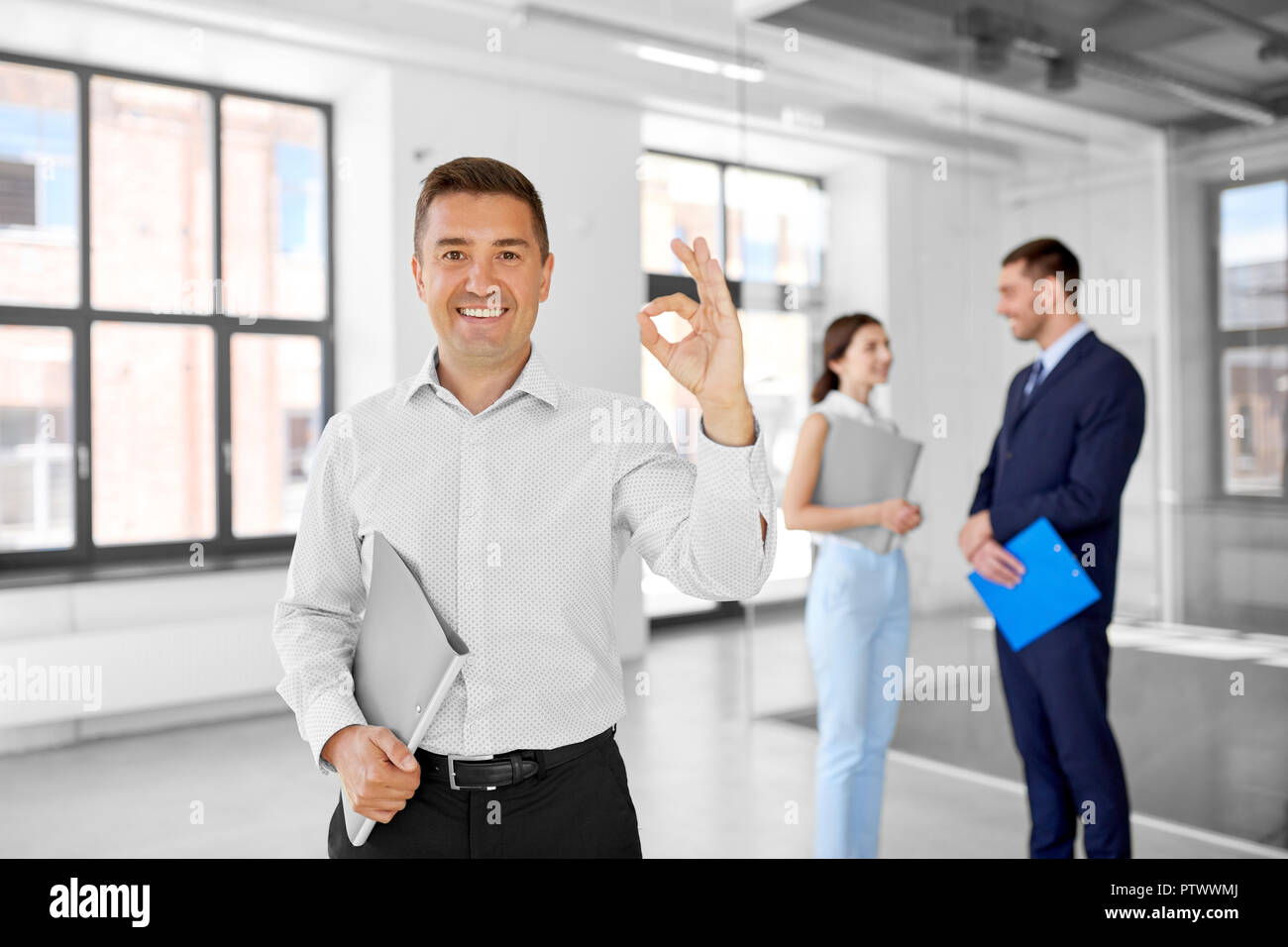 realtor with folder showing ok hand sign at office Stock Photo - Alamy