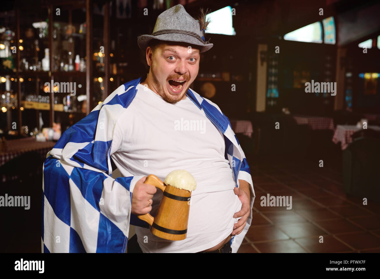 cheerful fat man with a mug of beer and with an oktoberfest flag in a ...