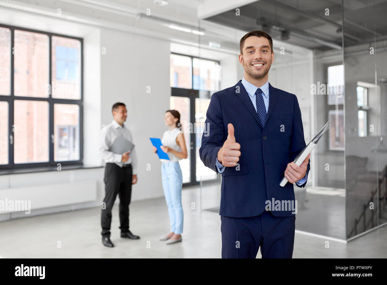 realtor with folder showing thumbs up at office Stock Photo - Alamy