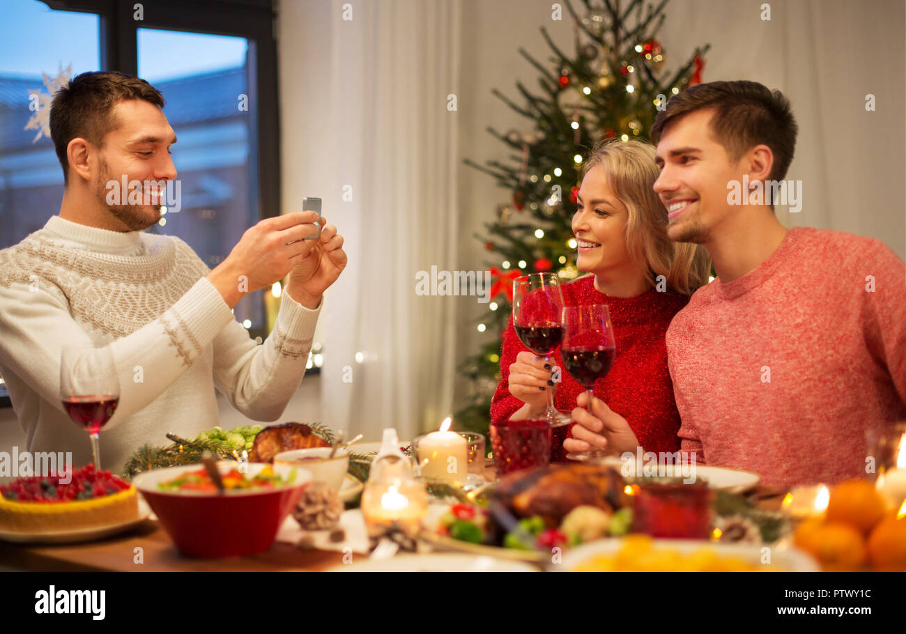 happy friends photographing at christmas dinner Stock Photo - Alamy