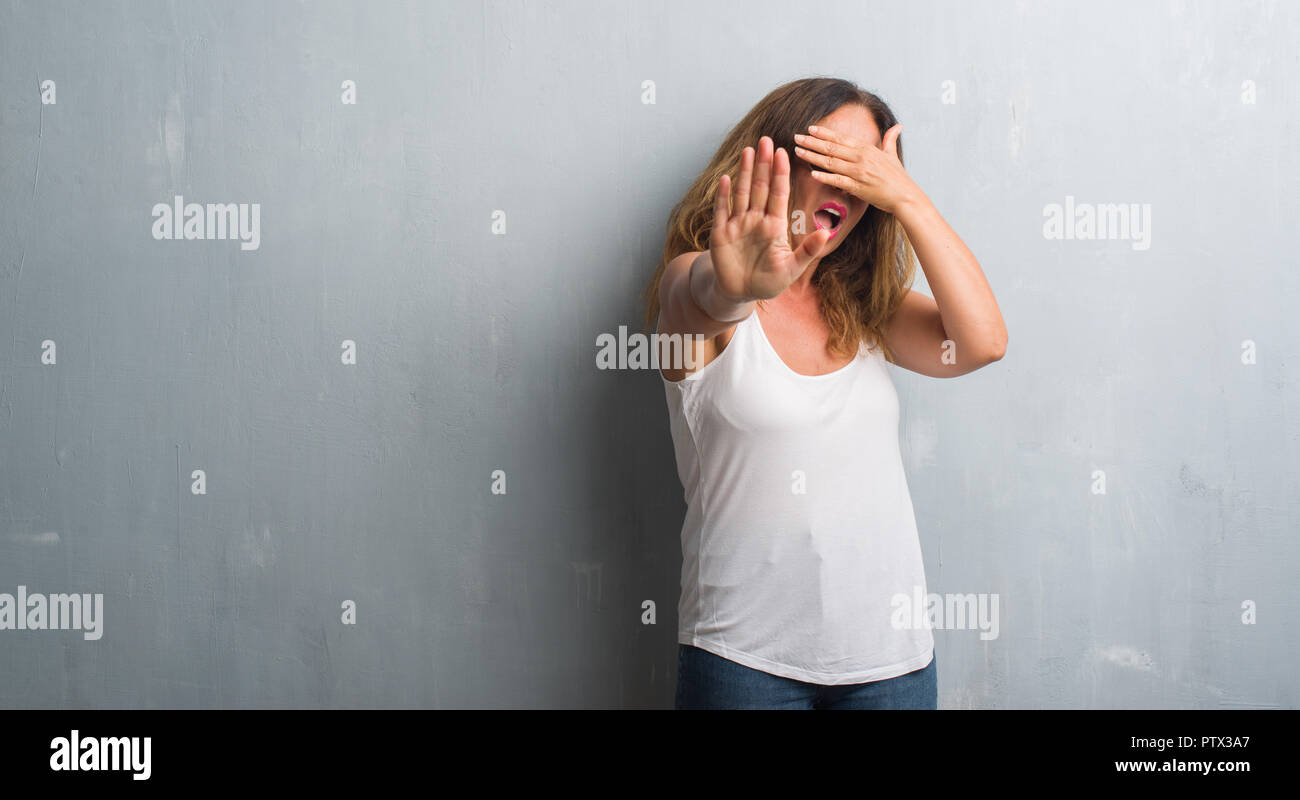Middle age hispanic woman over grey wall wearing sunglasses covering ...