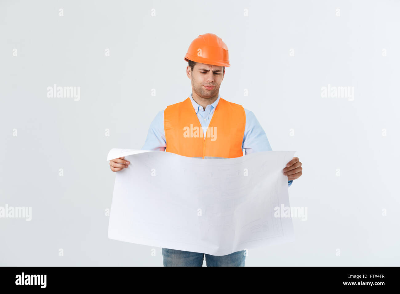 Thoughtful architect holding blueprints against white background Stock ...