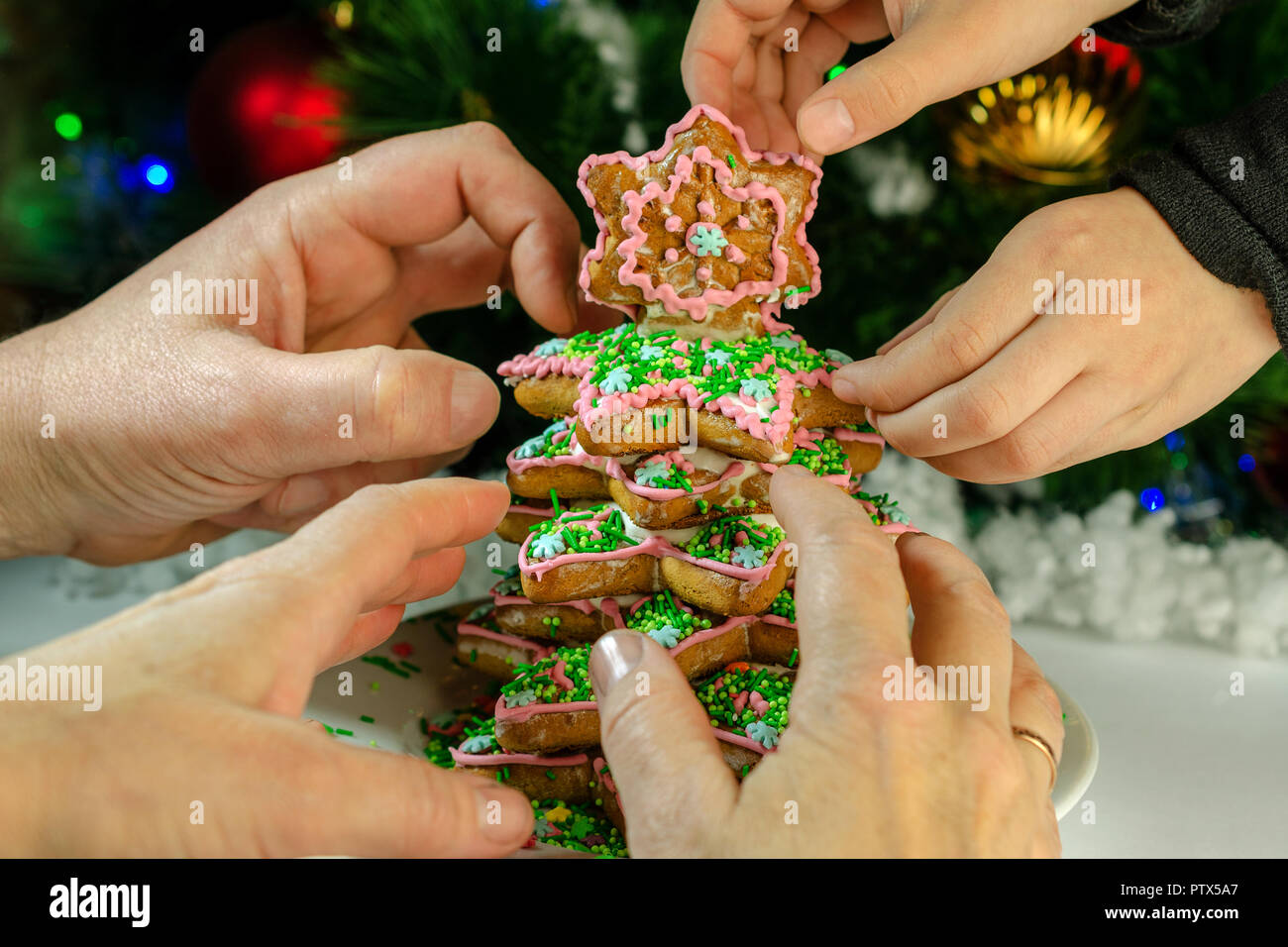 Human hands reach for the pieces gingerbread tree on the background of ...