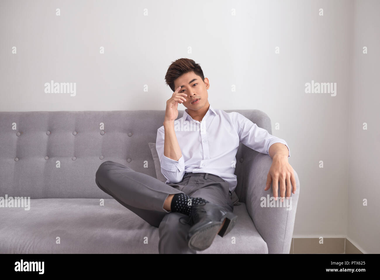 Happy man relaxing on couch at home in the living room Stock Photo - Alamy
