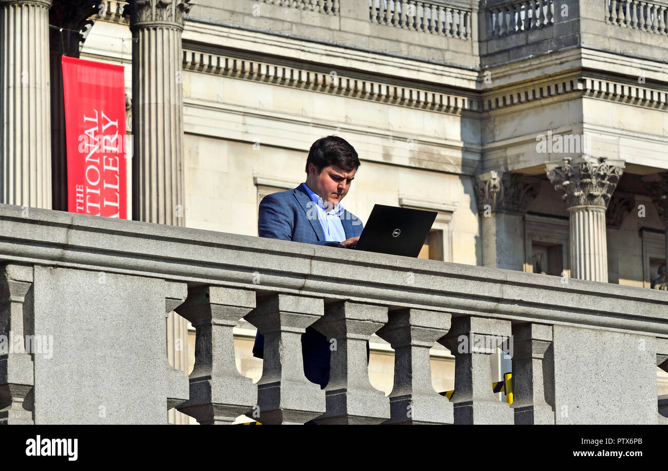 Businessman using his laptop computer in Trafalgar Square, London ...