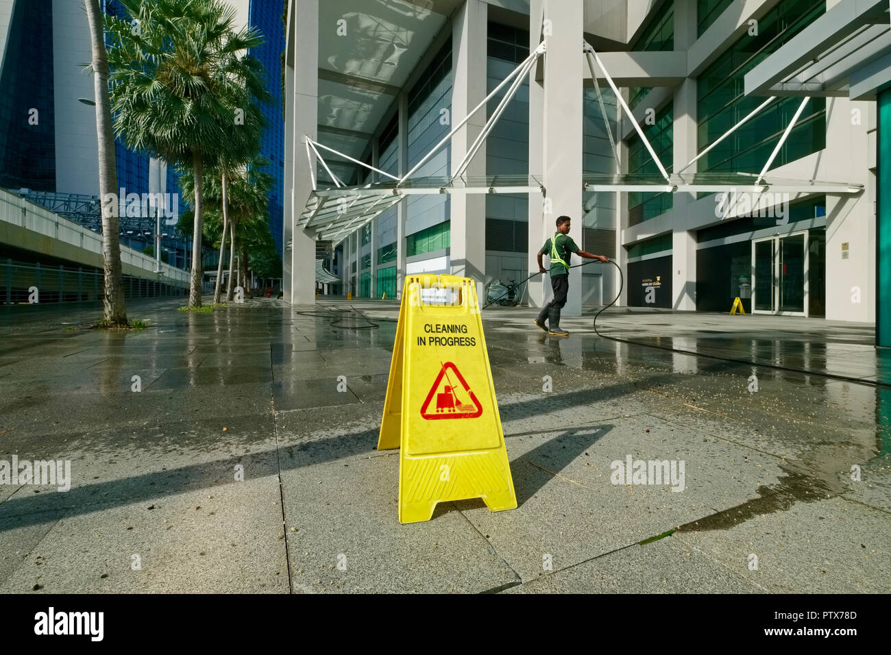A foreign worker cleaning the footpath at The Shoppes at Marina Bay ...