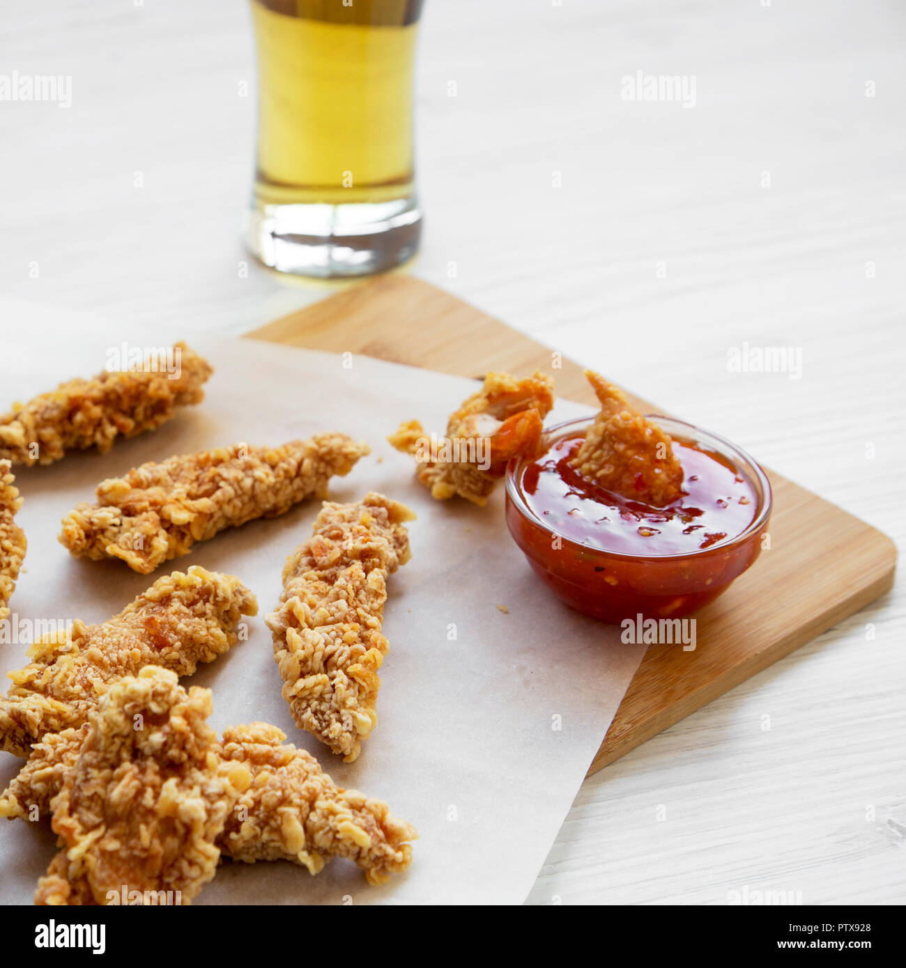 Chicken fingers served with sauce and cold beer. White wooden table ...