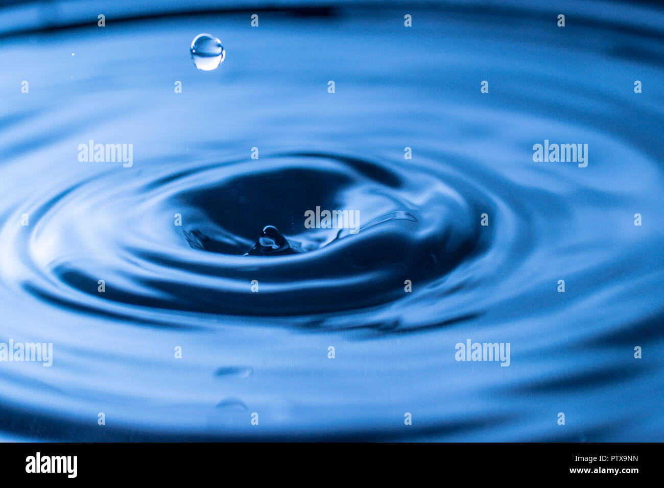 water drop splash in a glass blue colored Stock Photo - Alamy