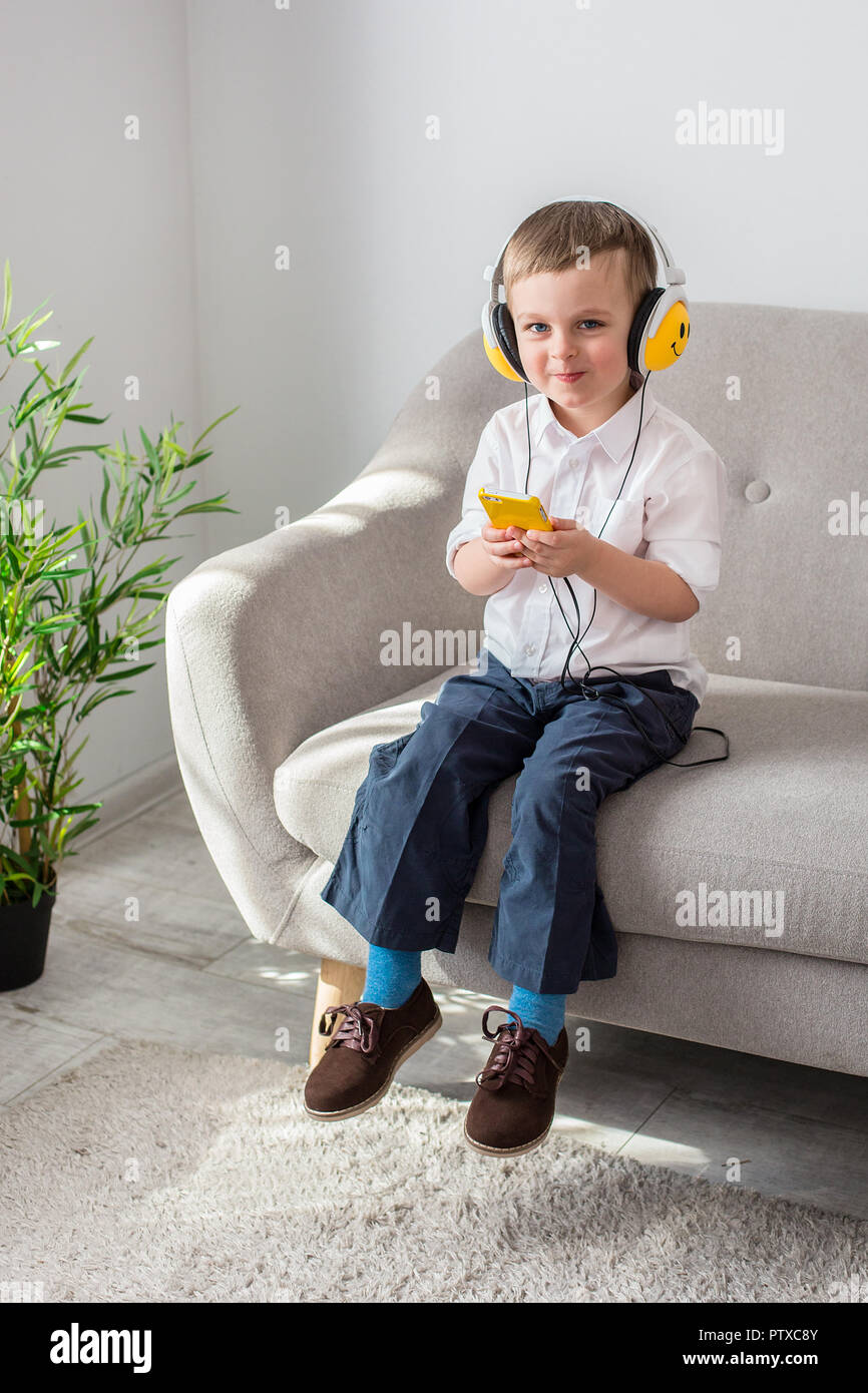 boy listening to music with headphones sitting on the couch Stock Photo ...