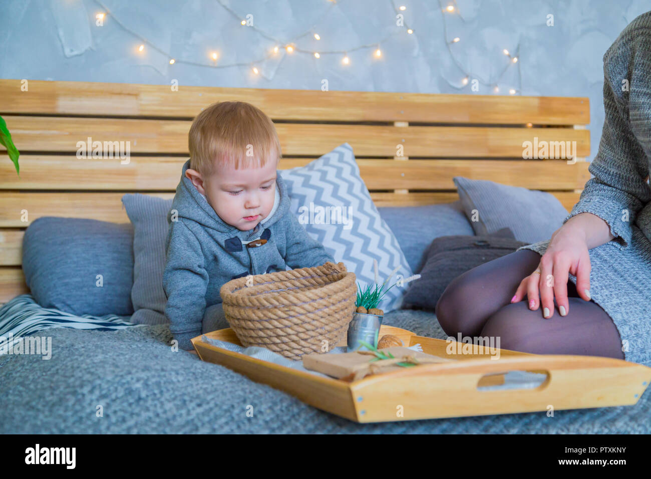 Happy young mother and her baby son playing with walnuts on the bed ...