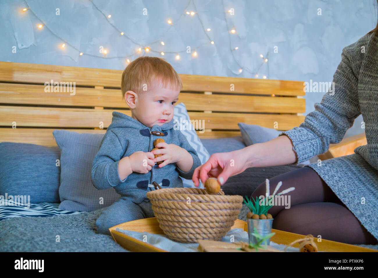 Happy young mother and her baby son playing with walnuts on the bed ...