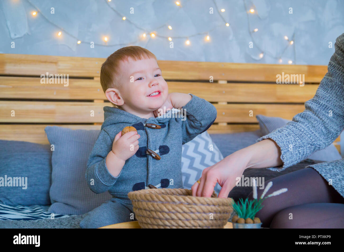Happy young mother and her baby son playing with walnuts on the bed ...
