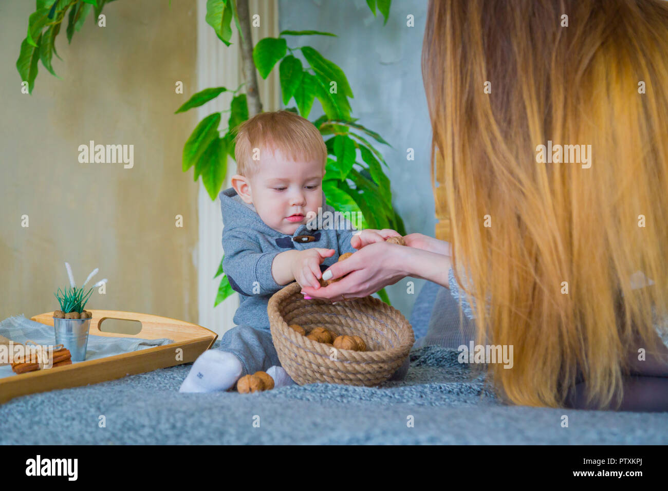 Happy young mother and her baby son playing with walnuts on the bed ...