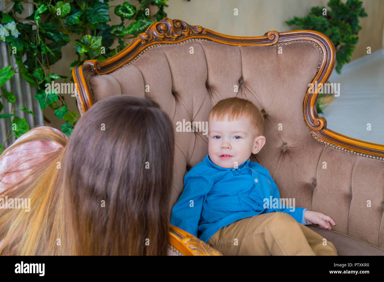 Little happy boy sitting on the chair at home Stock Photo - Alamy