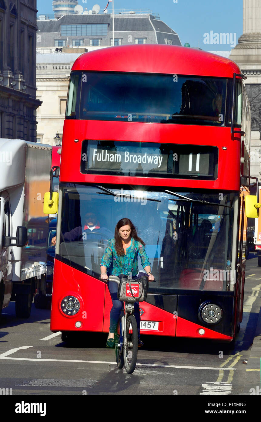 Woman cycling in front of a Red London bus in Whitehall, London, England, UK Stock Photo - Alamy