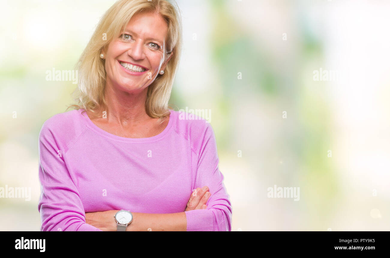 Middle age blonde woman over isolated background happy face smiling with crossed arms looking at ...