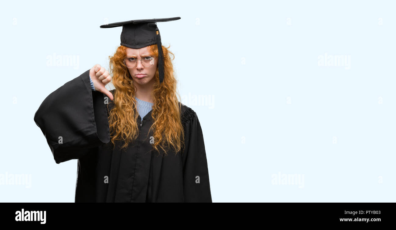 Young redhead student woman wearing graduated uniform with angry face ...