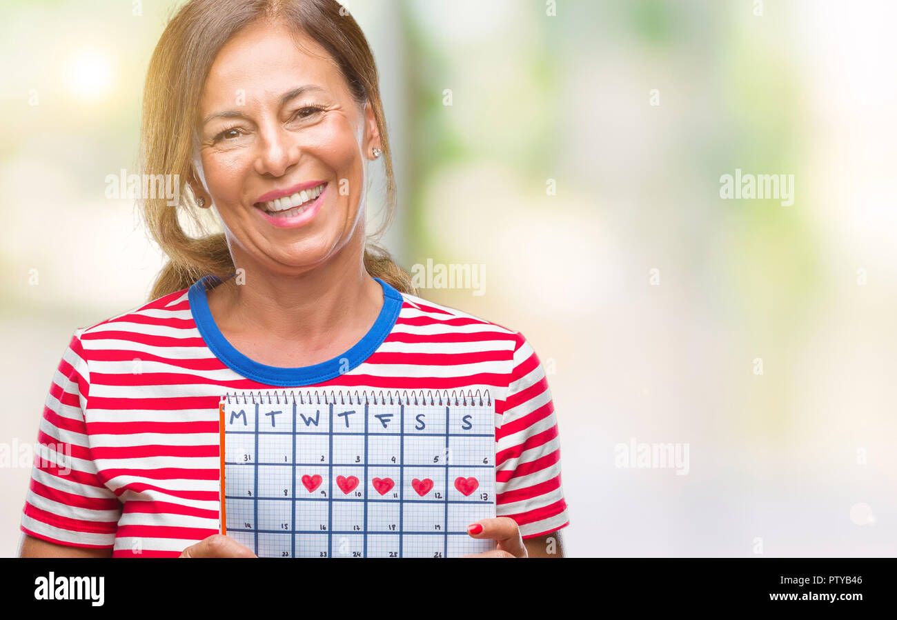 Middle age senior hispanic woman holding menstruation calendar over ...