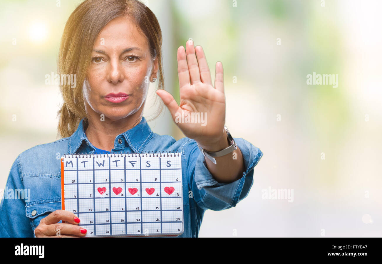 Middle age senior hispanic woman holding menstruation calendar over ...