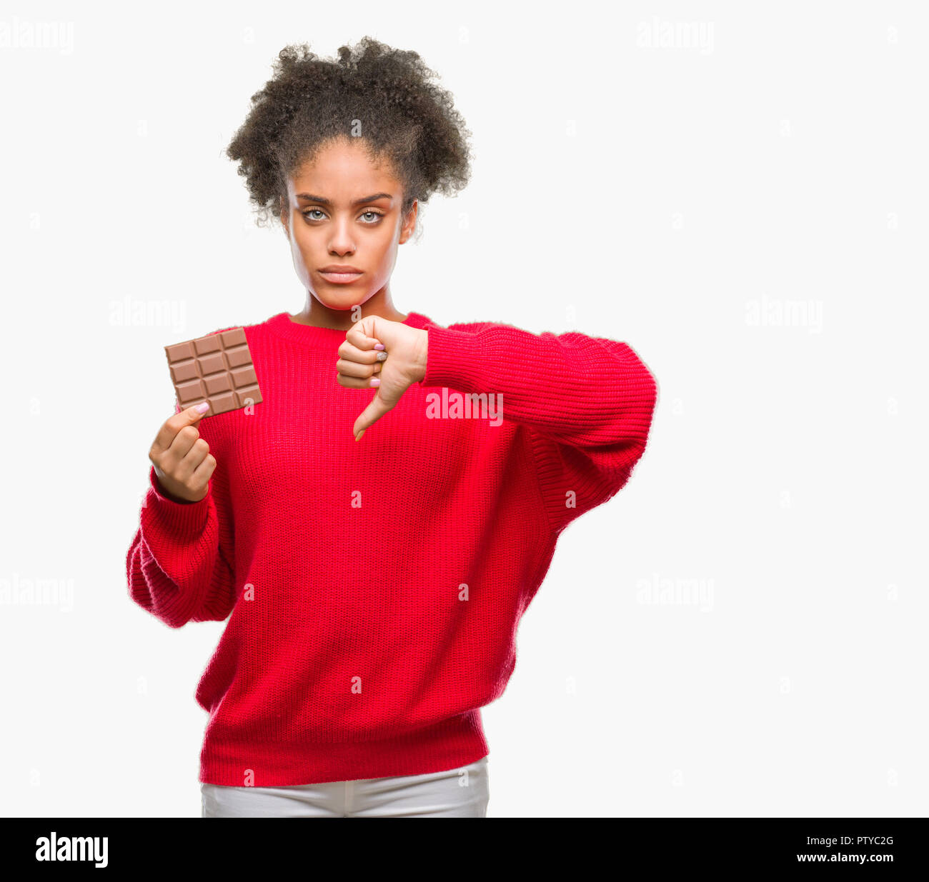 Young afro american woman eating chocolate bar over isolated background ...