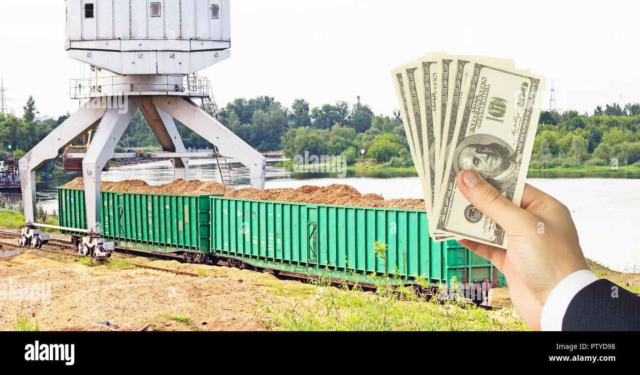 Hand with money dollars on the background of a port crane produces the ...