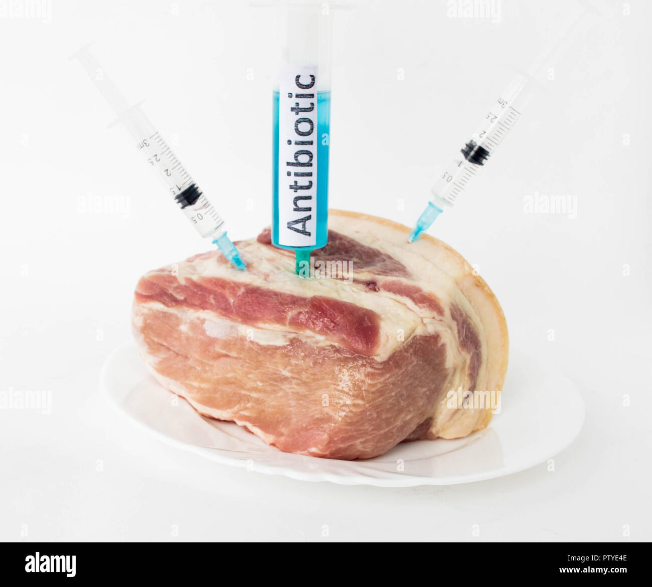On the plate lies a piece of pork meat in it syringes with an ...