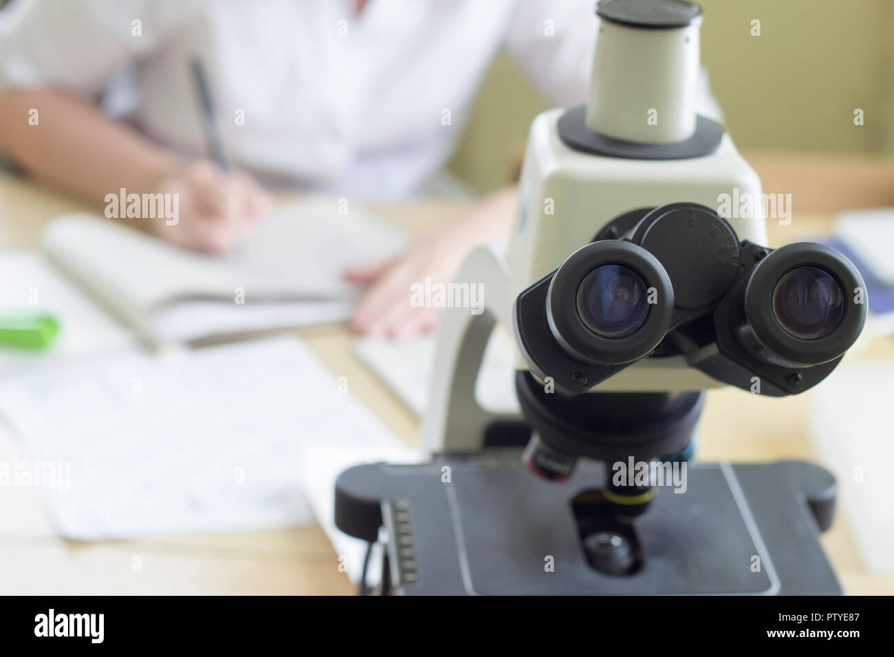 medical microscope, in the background a doctor filling out test results ...