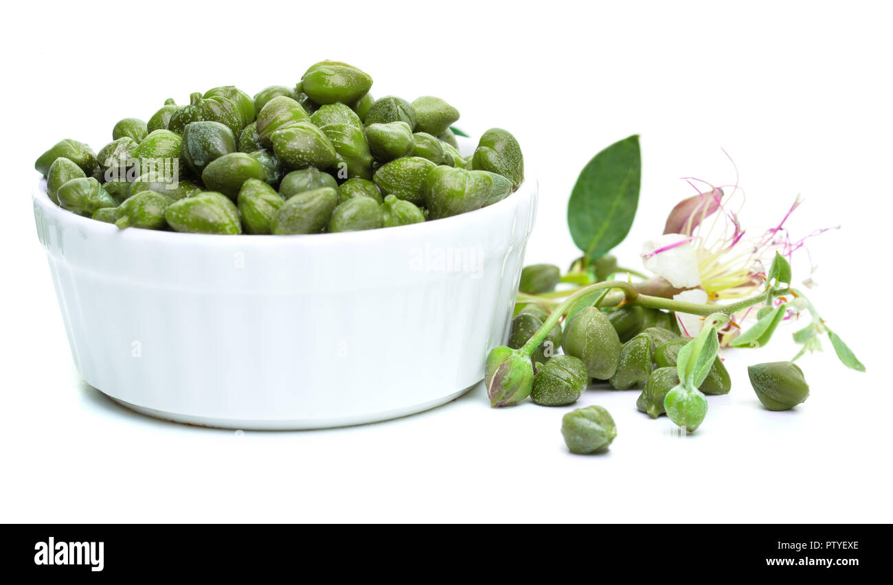 Capers, green leaves and caper flower in white bowl on white background ...