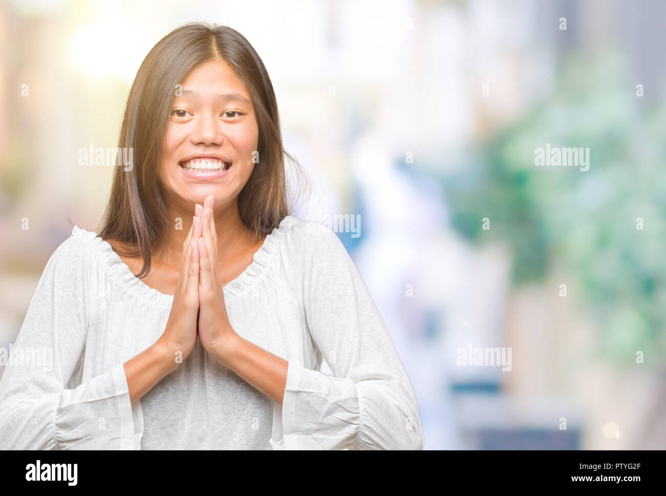 Young asian woman over isolated background praying with hands together ...