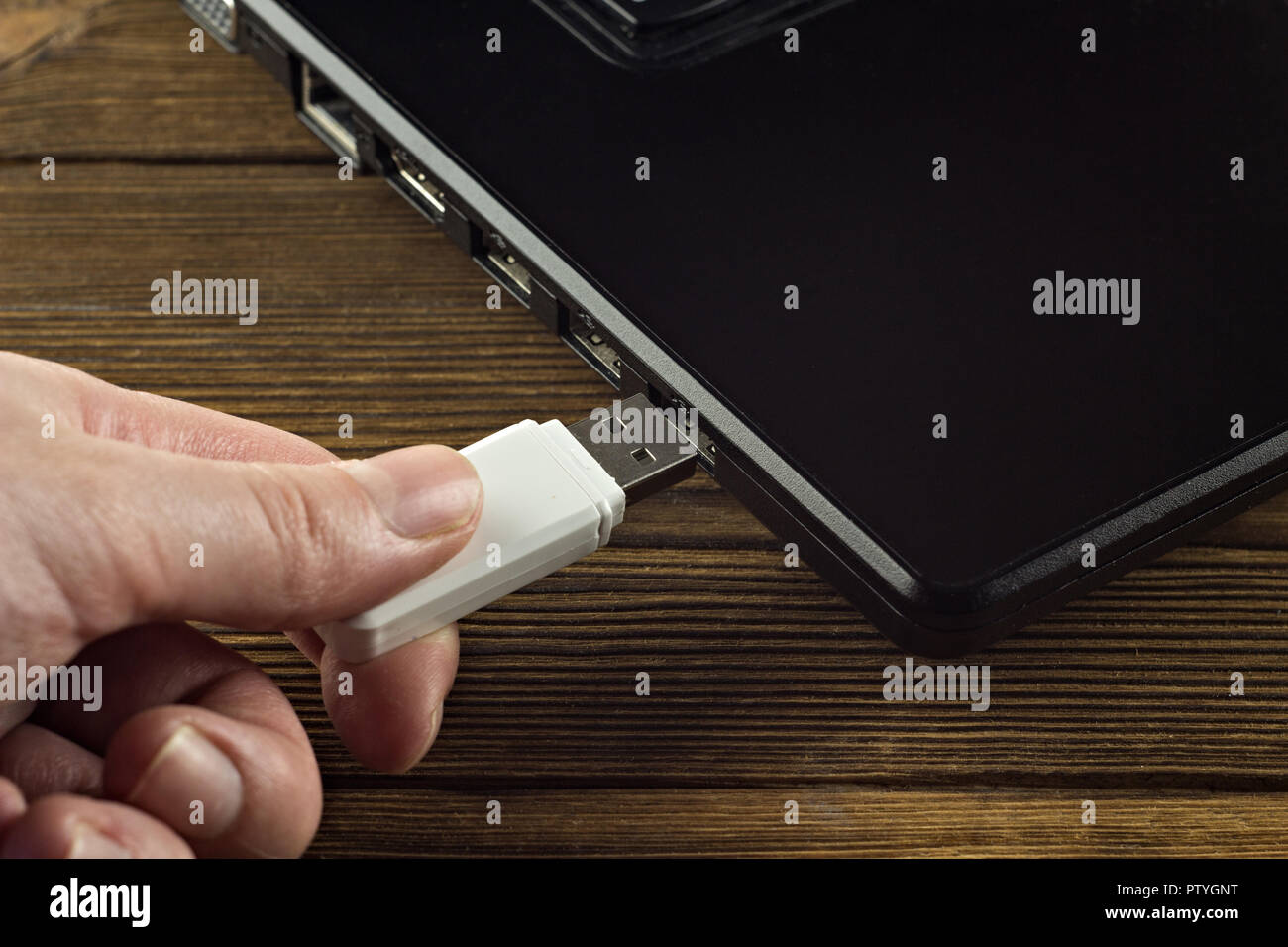 The hand inserts a white USB flash drive into the input of a black ...