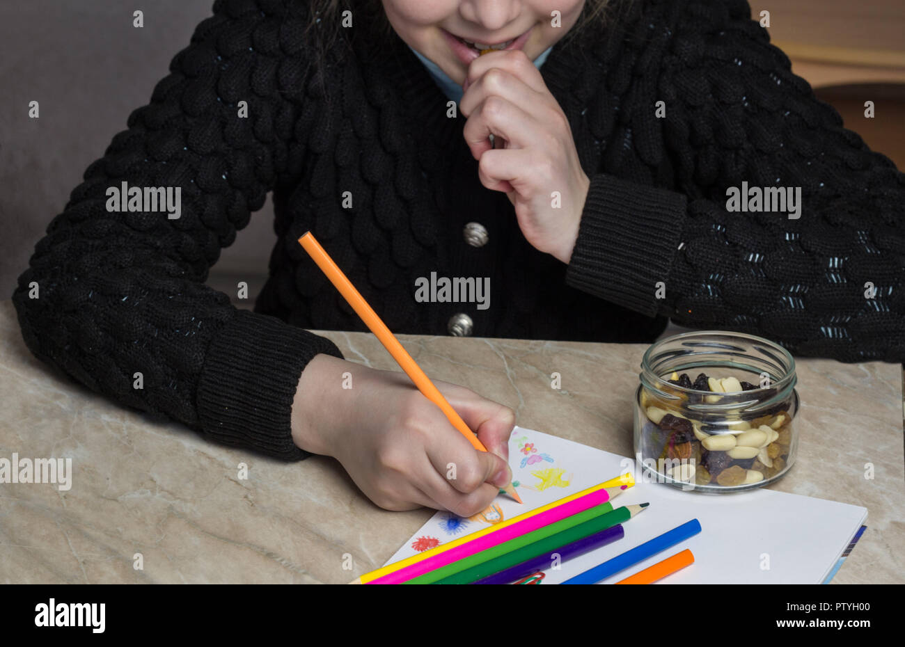 Girl doing homework and eating dried fruits Stock Photo - Alamy